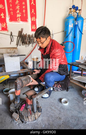 Heqing, China - March 16, 2016: Bayi woman making a silver pot. Heqing ...