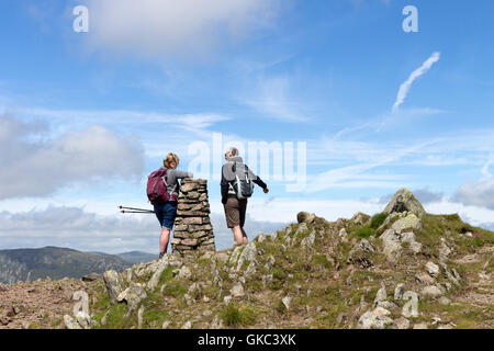 A walker on the summit of Red Screes at sunset in the Lake District, UK ...
