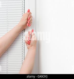 finger on the blinds on the window of the house, look out the window ...