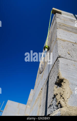 Builder's plumb line hanging against exterior corner wall of house ...