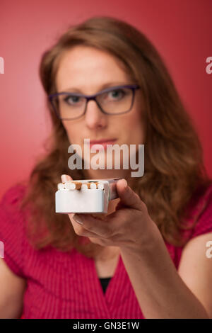 woman offering a cigarette over red background Stock Photo - Alamy
