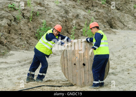 Workers pulling roll high voltage cable line Stock Photo - Alamy