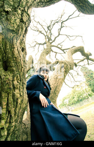 A beautiful sad goth girl stands in autumnal field. Grunge texture ...