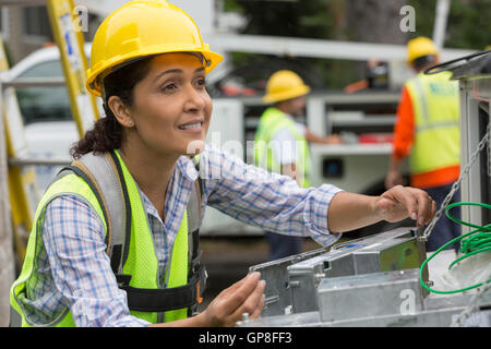 Hispanic female utility worker working with line amplifiers at site ...
