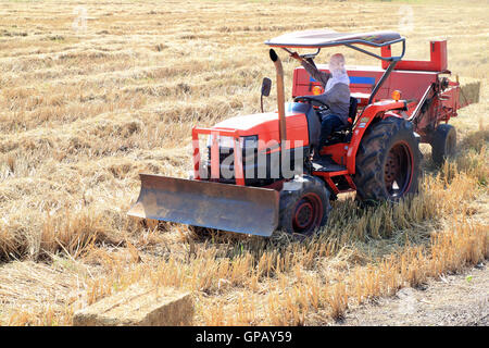 farmer and tractor packing straw in the field at Thailand Stock Photo ...