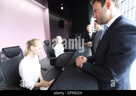 Business people filling forms at front desk Stock Photo - Alamy