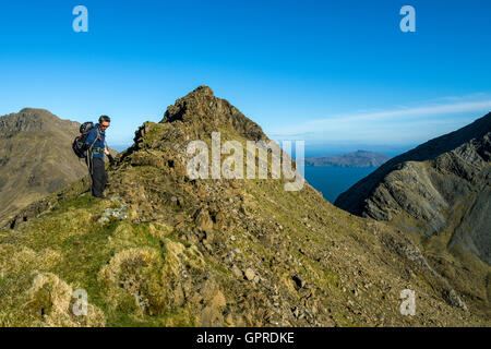Walker on the summit ridge of Trollabhal in the Rum Cuillin hills, Isle ...