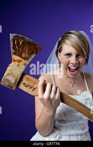Bride in a blood-stained wedding dress holding a knife in a studio ...