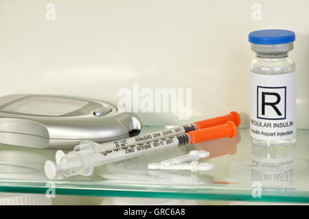 Vial of regular insulin and syringe on medicine cabinet shelf. Labels ...