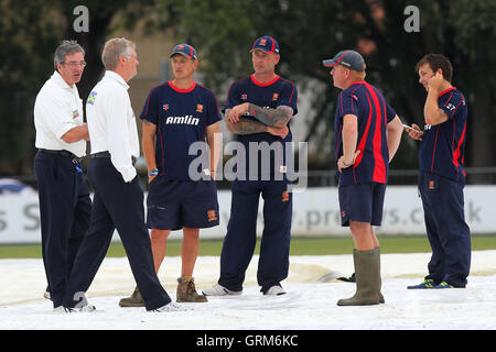 Umpires Nick Cook (L) and Steven Garratt meet with groundsman Stuart ...