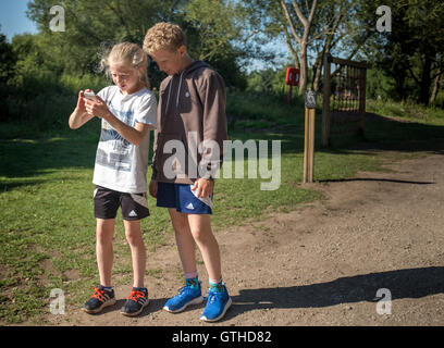 Two children playing Pokemon Go in the countryside Stock Photo - Alamy