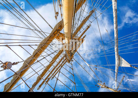 Detail of main mast of tall ship with two seamen on top yard securing ...