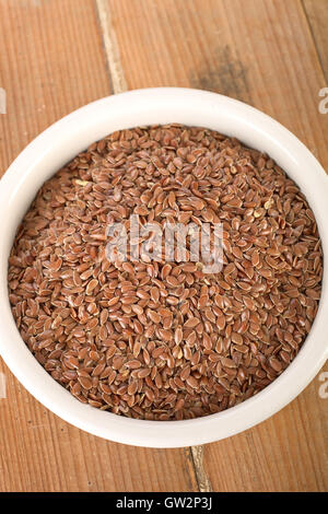 Flax seeds in bowl, wooden scoop and flaxseed oil in glass bottle on wooden tray over rustic ...