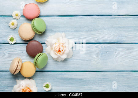 Tasty french macarons with flowers on a red background. Place for text ...