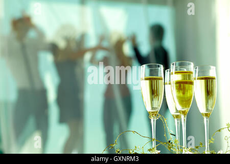 Colleagues dancing with glasses of champagne at a New Year's party in ...