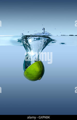 Lime falls into water on a blue background Stock Photo - Alamy