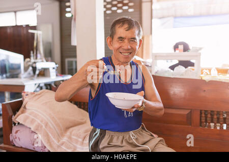 Smiling senior man eating rice and smiling young woman eating pizza ...