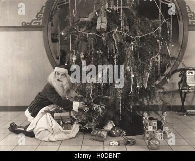 Santa Claus putting presents under a Christmas tree isolated on white ...