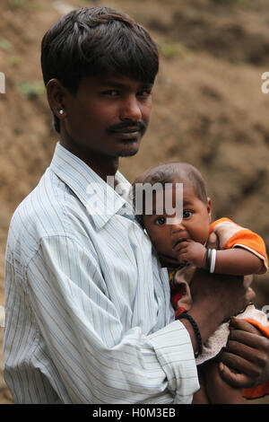 Poor indian baby boy holding on to a bike wheel. Andhra Pradesh, India ...