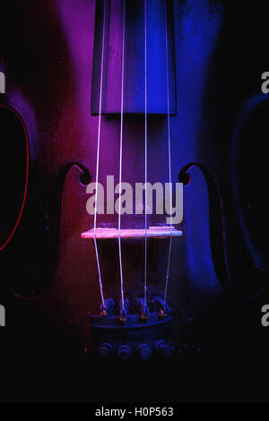 Studio composition of an old dusty violin, blue and purple illumination ...