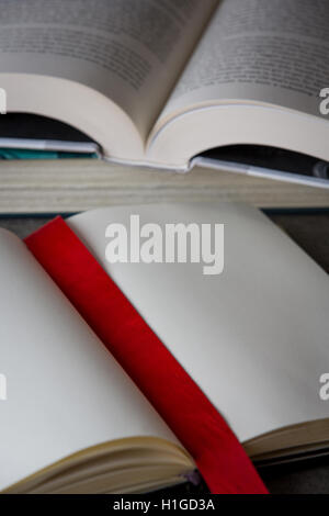Multiple open books on table, one marked with a red ribbon Stock Photo ...