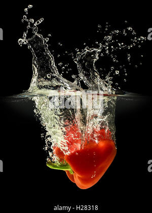 Red bell pepper falling in water on black Stock Photo - Alamy