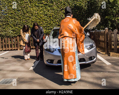 A Shinto priest performs a purification ritual by waiving a harai-gushi ...