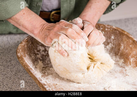 Woman kneading dough in a dough trough until it is smooth and elastic ...