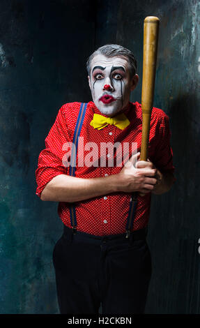 The scary clown and baseball-bat on dack background. Halloween concept ...