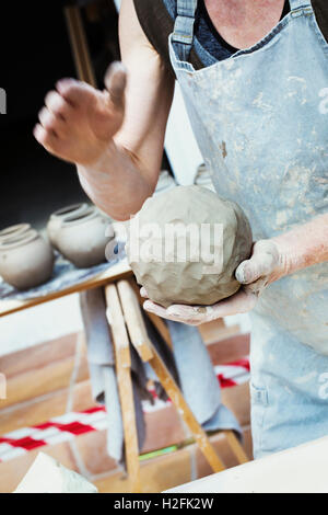 A potter handling a wet clay pot, smoothing clay and preparing it for ...