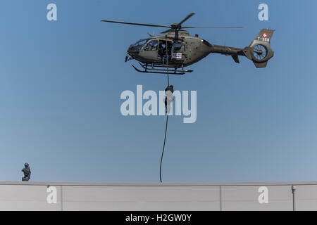 Armed policeman abseiling from helicopter onto roof, body armour ...