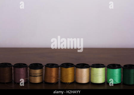Scattered coloured cotton reels on a wooden surface Stock Photo - Alamy