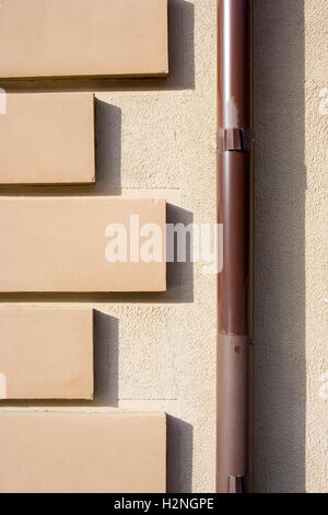facade of a building wall with a downspout pipe and a concrete dish ...