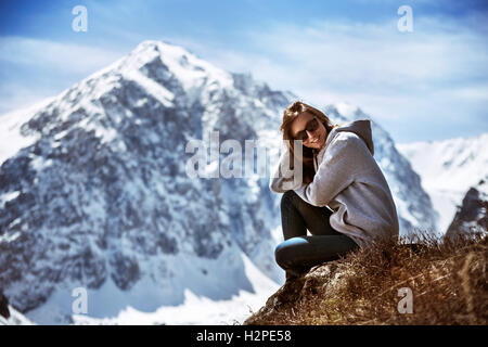 Female traveler sits on peak of mountain with closed eyes on background ...