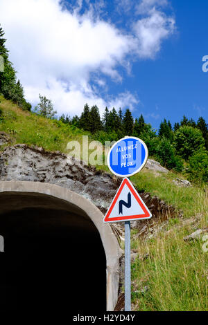 Road tunnel with "allumez vos feux" sign near summit of Col des Aravis ...