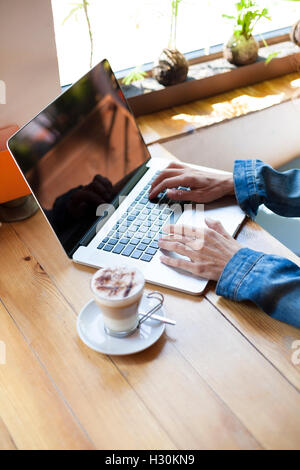 woman with blue jeans jacket typing on keyboard pc laptop next to ...