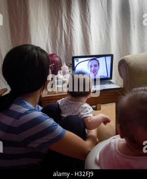 Smiling mother daughter twins watching cartoon video on laptop before ...