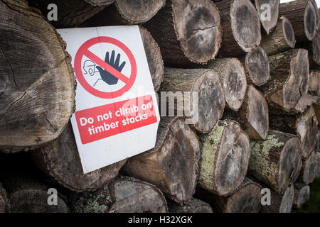 warning do not climb on timber stacks sign next to a pile of logs in ...