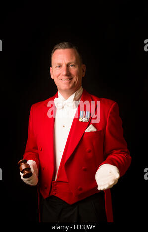 Toastmaster against a black background in traditional red jacket with ...