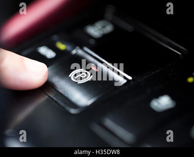 Hand pressing the electric parking brake button in an electric vehicle ...