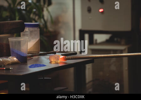 Glassblower rolling molten glass over frit glass on a marver table ...