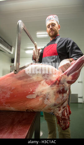 Butcher cutting pigs head with a saw Stock Photo - Alamy