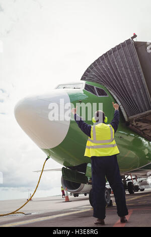 Rear view of airport ground crew worker directing airplane Stock Photo ...