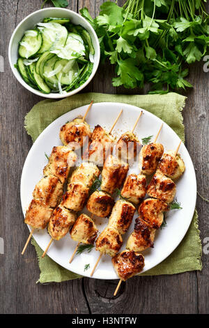 Grilled chicken kebab and salad with cucumber, radish, onion on a dark ...