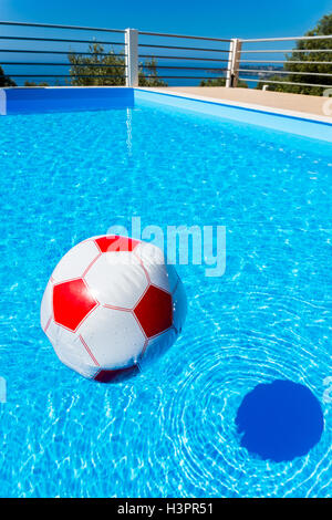 Floating red beach ball in swimming pool Stock Photo - Alamy