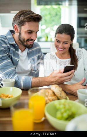 Couple using mobile phone while having coffee Stock Photo - Alamy