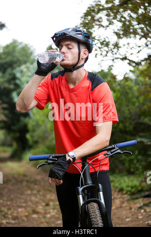 Cyclist sportsman holding bottle of water, having a break while riding ...