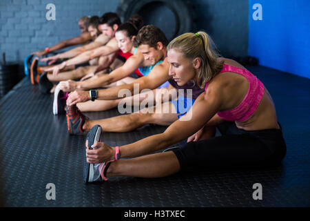 Side view of man stretching on wooden walkway by river against sky ...