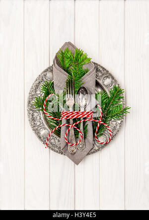 Christmas tree branch, ornaments and cutlery on a white wooden table ...