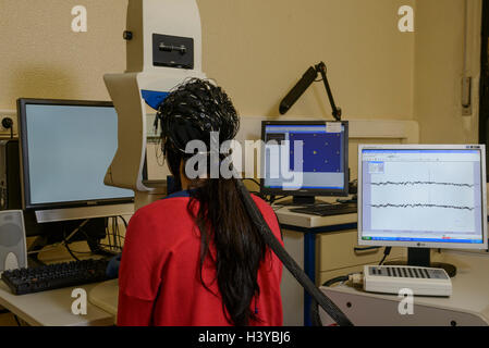 Person undergoing an electroencephalogram with an EEG cap to scan her ...